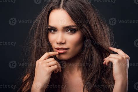 jeune et coquette belle jeune femme torse nu touchant ses lèvres et