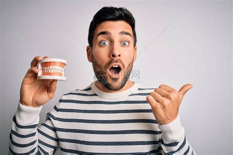 长着胡子的英俊男子拿着塑料假牙在白色背景上高清图片下载 正版图片503670030 摄图网