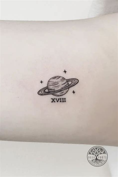 A Small Saturn Tattoo On The Left Inner Arm With Stars And An