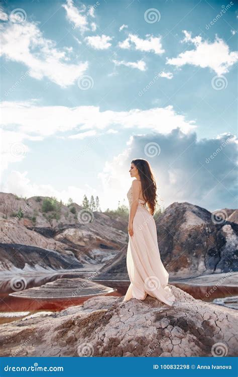 Brunette Woman In Long Dress Standing In The Wind On A Back Stock Photo