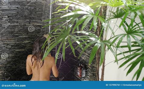 La Mujer Morena Joven Atractiva Toma Una Ducha En Cuarto De Baño Hermoso Con Las Plantas