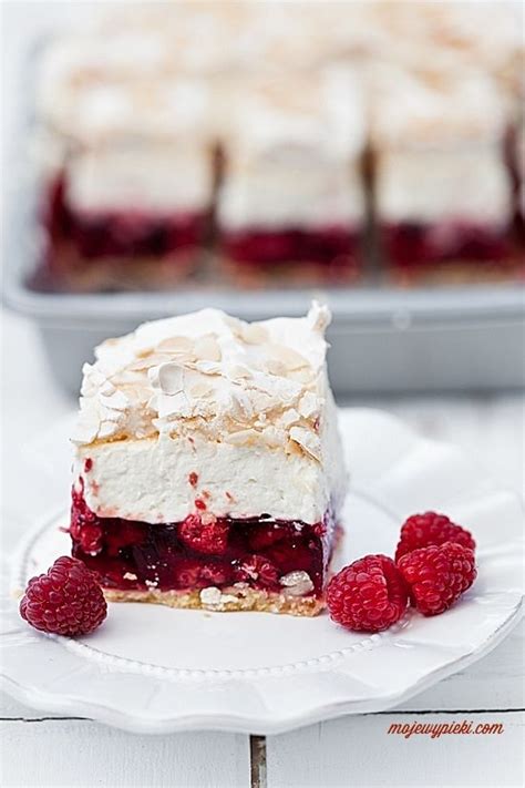 A Piece Of Cake On A Plate With Raspberries And Another Slice In The