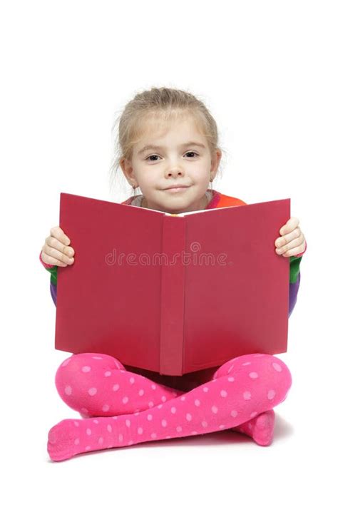 Petite Fille S asseyant Sur L étage Affichant Le Livre Image stock