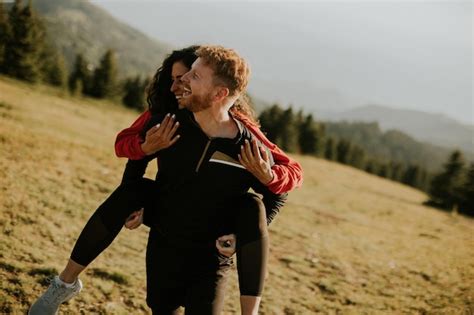 Mujer joven equitación piggyback en un novio en verde colinas