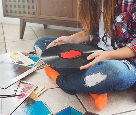 Teen Holds 33 LP Vinyl Record While Sitting On Floor With Albums By