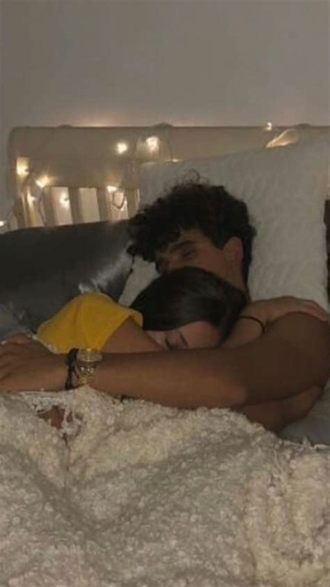 A Man And Woman Laying In Bed With Their Arms Around Each Other Cuddling