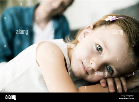 Une petite fille couchée sur un canapé son père debout dans l arrière
