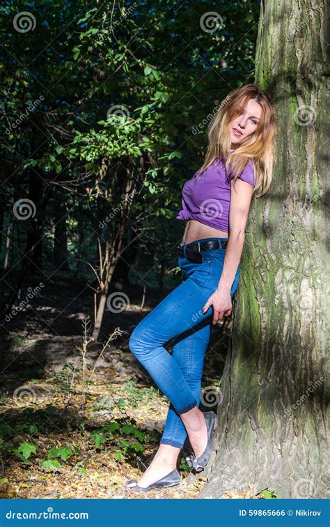 Young Beautiful Girl Blond Model With Long Blond Hair In Jeans And Jacket Posing In The Woods