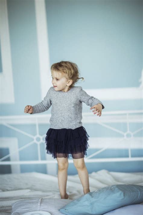 Vieille Fille De Cinq Ans Heureuse Sautant Sur Le Lit Photo Stock