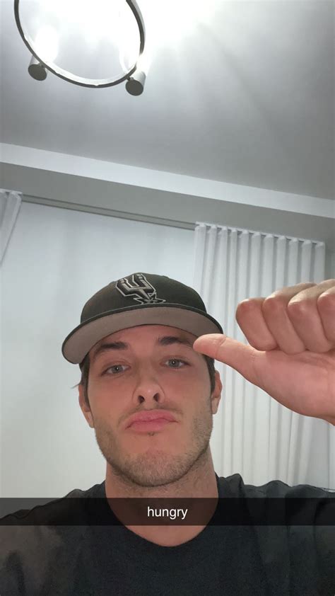 A Man In A Black Shirt And Hat Holding His Hand Up To The Camera Lens