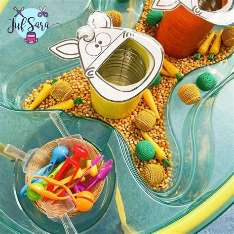 A Plastic Tray Filled With Toys On Top Of A Blue Table Covered In Sand