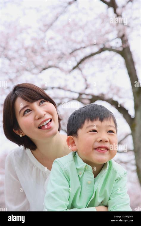 Madre e hijo japonés con los cerezos en flor en un parque de la ciudad