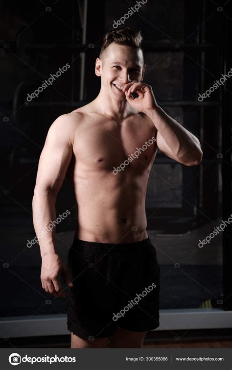 A Muscular Guy With A Naked Torso Stands In The Gym And Looks In Frame