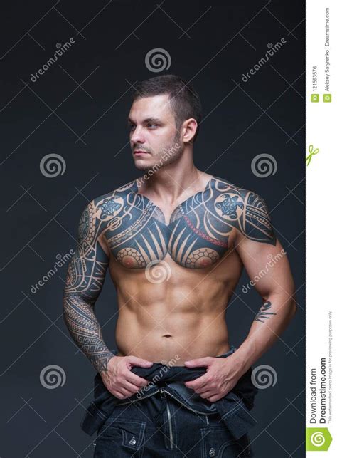 The Man With A Muscular Naked Torso With Tattoos On The Dark Background