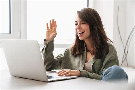 Smiling Woman Waving Hand While Taking Video Call On Laptop In 2024