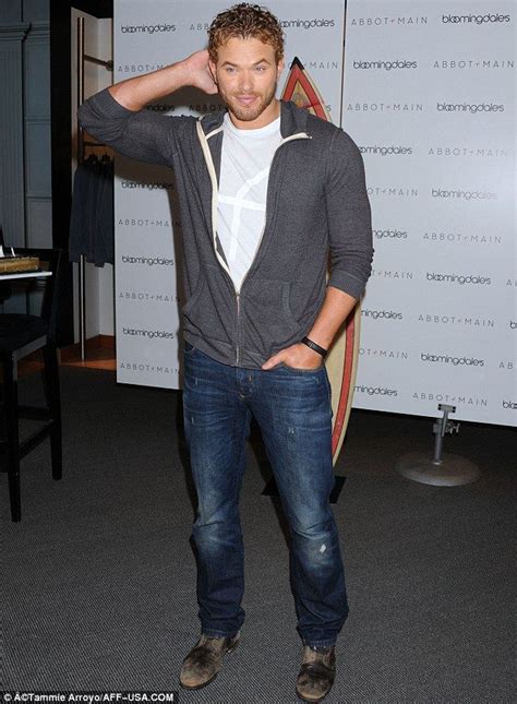 A Man Standing In Front Of A Wall With His Hand On His Head And Looking At The Camera