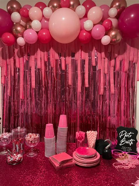 A Table Topped With Lots Of Pink And White Balloons Next To A Wall