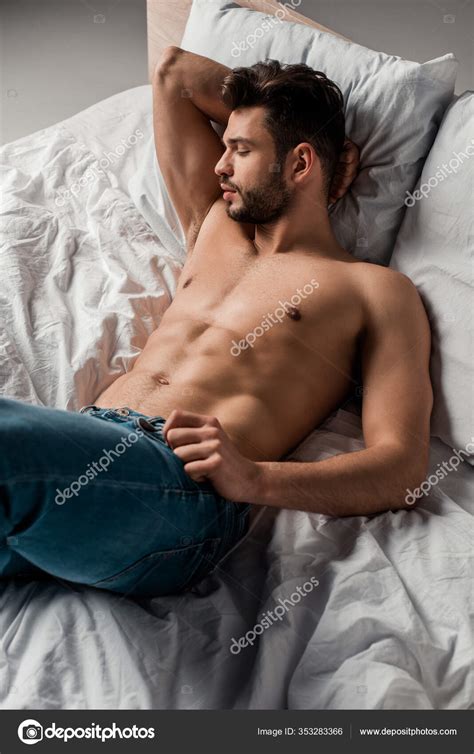 Seductive Shirtless Man Jeans Lying Bed Grey Stock Photo