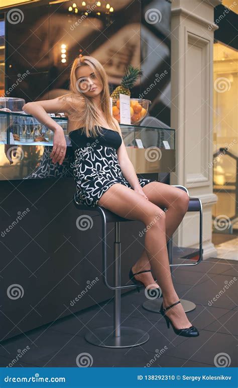 Muchacha Rubia Atractiva Con El Pelo Largo Que Se Sienta En Un Alto