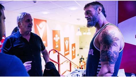 Two Men Standing Next To Each Other Talking