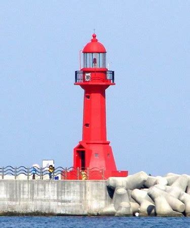 A Red Light House Sitting On Top Of A Pier Next To The Ocean