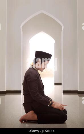 Side View Of A Man Kneeling And Praying Against Cloudy Sky At Sunset
