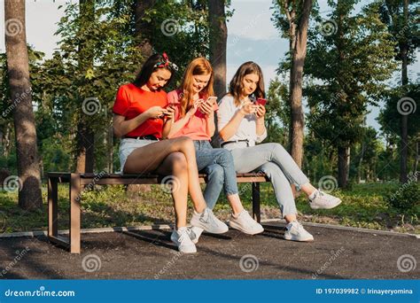 Trois Filles Causant Avec Leurs Téléphones Au Parc Jeune Copine GEN Z