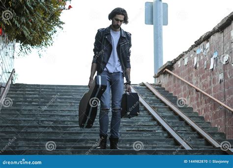 M Sico De La Calle Que Sostiene Un Caso Con Una Guitarra Y Un