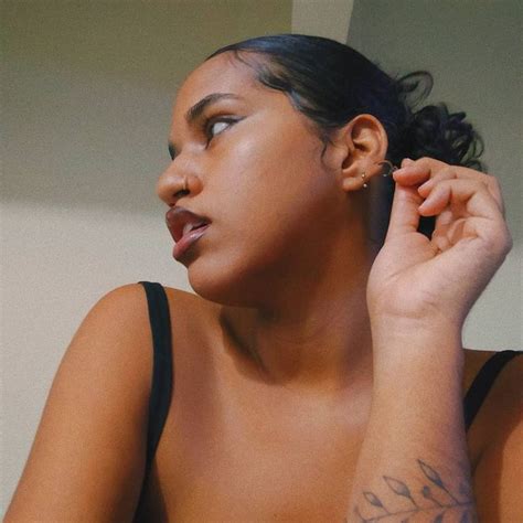 A Close Up Of A Person With Tattoos On Her Arm And Hand Near Her Ear