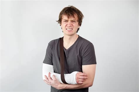 Brazo roto joven infeliz hombre caucásico con yeso en la mano que