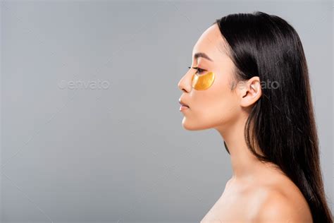 Side View Of Naked Asian Woman With Eye Patches On Face Isolated On