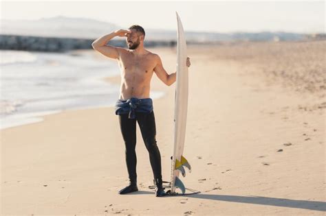 Un surfista atlético con el torso desnudo mirando a lo lejos Foto Premium