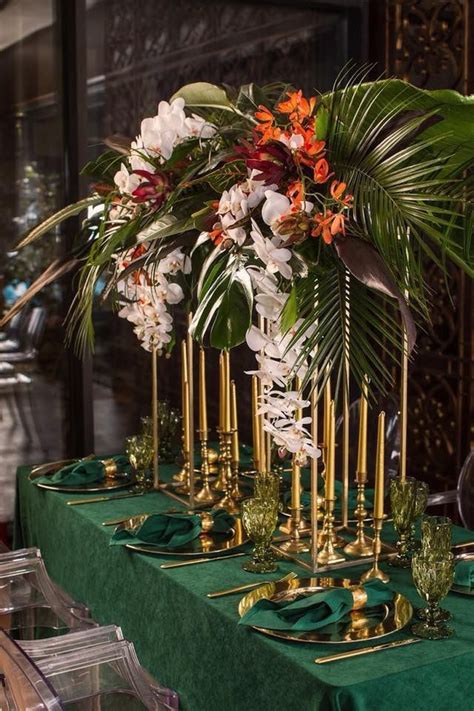 A Table Topped With Lots Of Green And Gold Place Settings Filled With