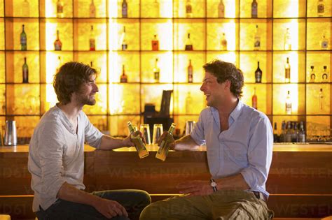 Two Men Sitting At Bar With Bottles Of Beer Stock Photo