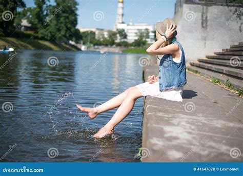 Fille S Asseyant Au Pilier Et Aux Pieds Nus Accrochants Photo Stock