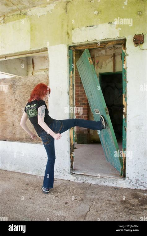 Pretty Red Haired Girl Wearing Jeans And T Shirt Kicking A Door In An