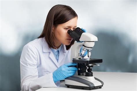 Grupo de cientistas que trabalham no laboratório ela usa microscópio