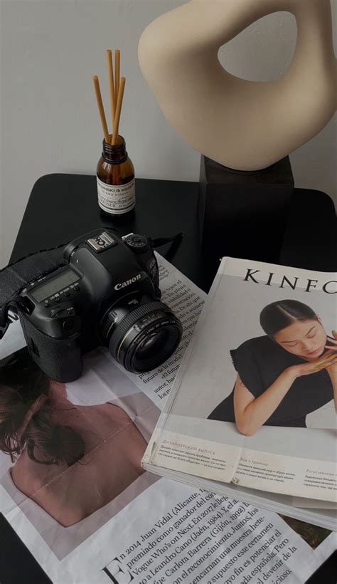 A Black Camera Sitting On Top Of A Table Next To A Magazine