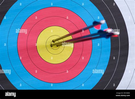 Three Arrows Embedded In The Dead Centre Of An Archery Target Focus On