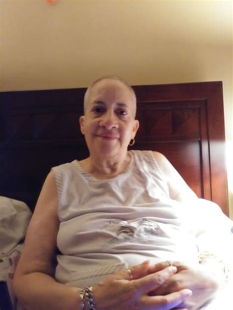 An Older Woman Sitting In Bed With Her Hands On Her Chest And Smiling