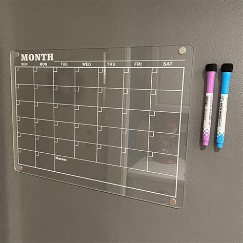 A Magnetic Dry Eraser And Marker Are On The Wall In Front Of A Calendar