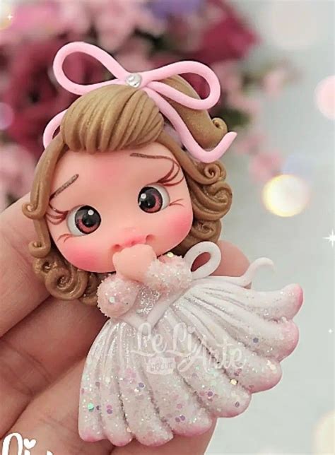A Hand Holding A Small Doll With A Pink Bow On It S Head And Wearing A
