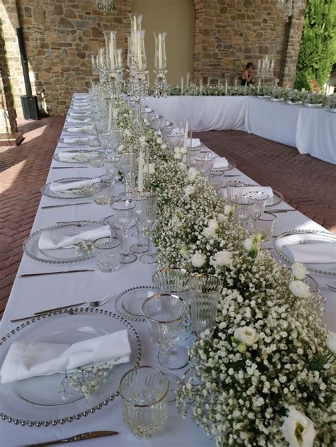 A Long Table With White Flowers And Place Settings