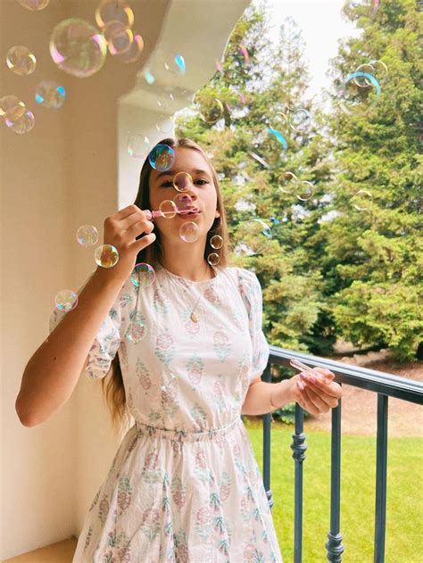 A Girl In A Dress Blowing Bubbles From Her Hands On A Balcony With