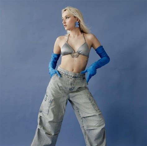A Woman Wearing Blue Gloves And Jeans Posing For A Photo