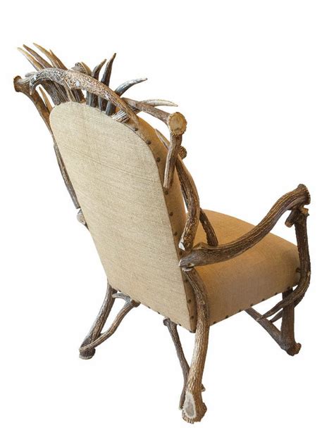 A Wooden Chair With Antlers On It S Back And Arm Rests Against A White
