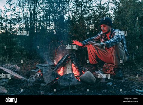 Man Sitting At Campfire In Rural Landscape Stock Photo Alamy