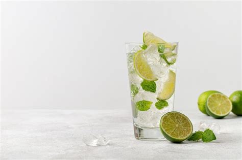 Vaso de limonada fría de mojito con lima helada y menta sobre mesa gris
