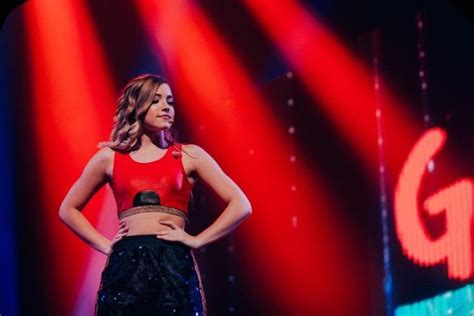 A Woman Is Standing On Stage With Her Hands On Her Hips And Looking Off