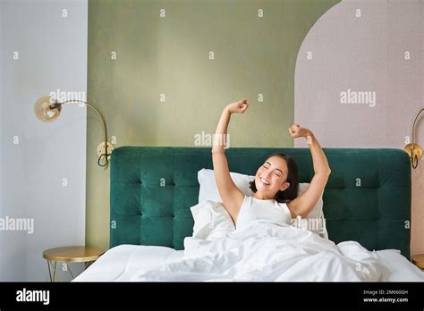 Portrait Of Smiling Happy Asian Girl Wakes Up Feeling Enthusiastic Stretches Her Hands Up